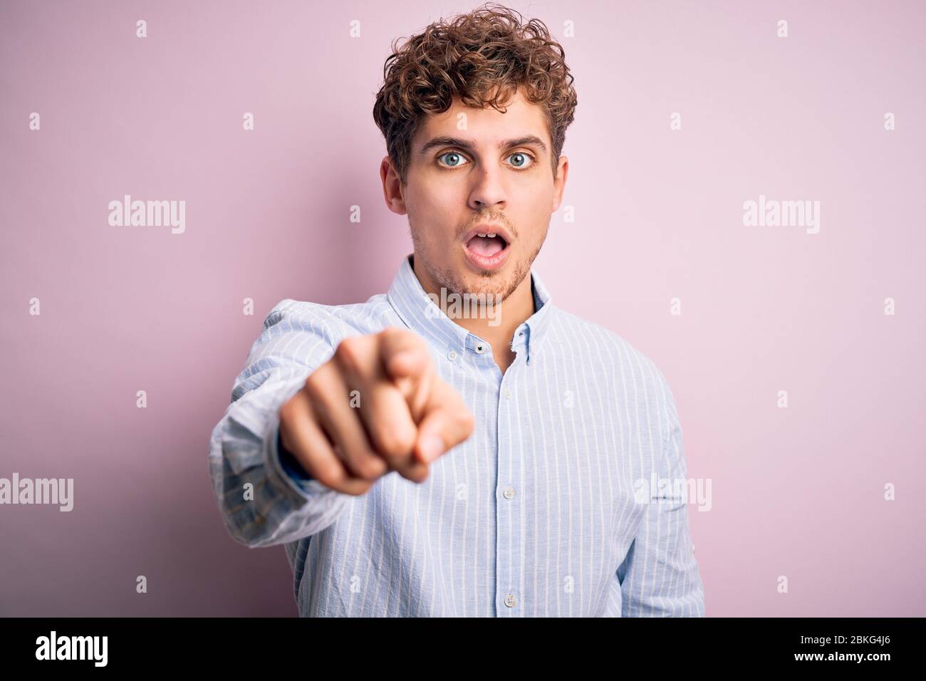 Young blond handsome man with curly hair wearing striped shirt over ...