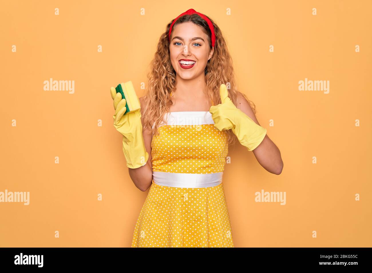 Young beautiful blonde woman with blue eyes cleaning using gloves and ...