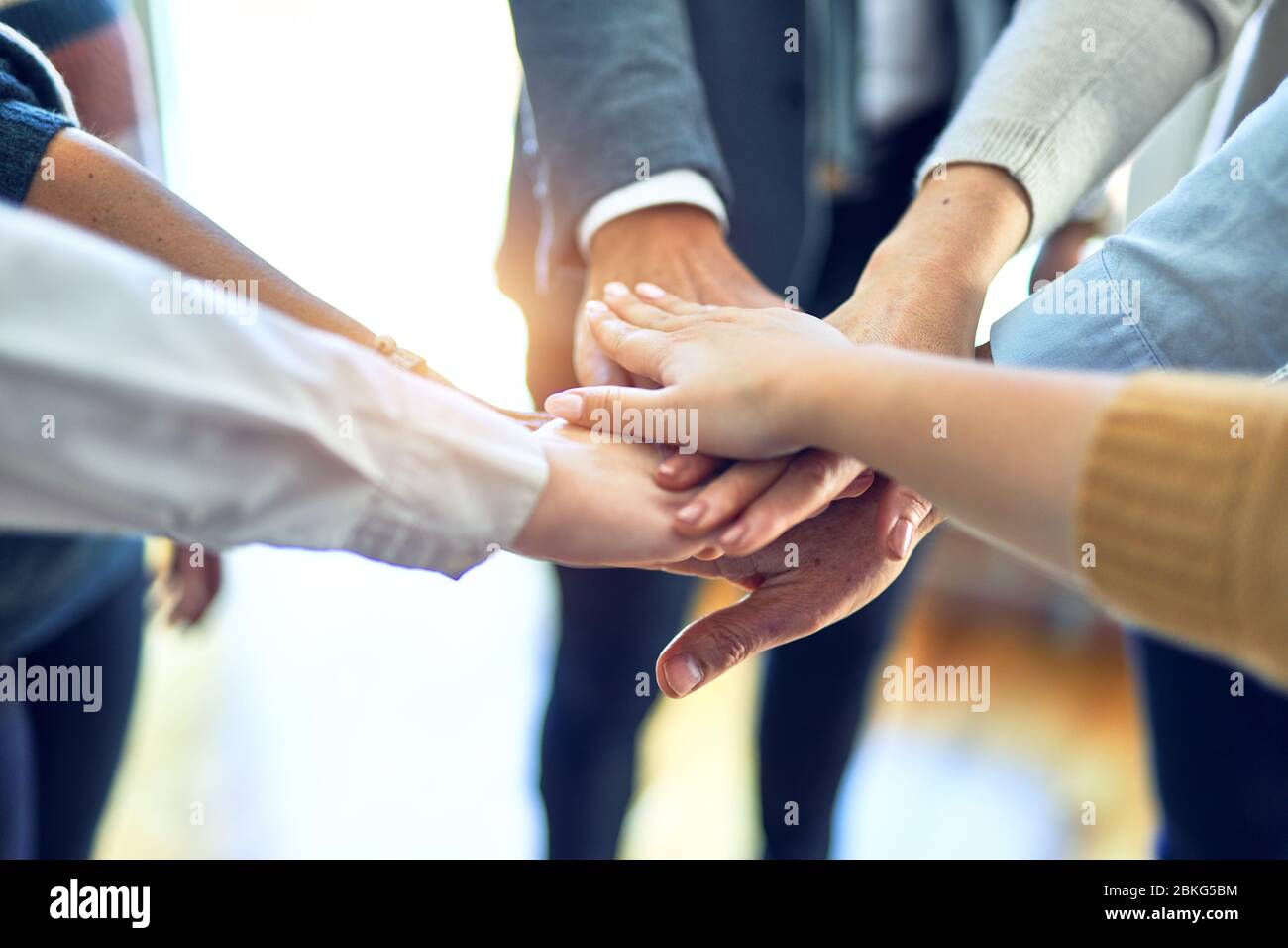 Group of business workers standing with hands together at the office ...