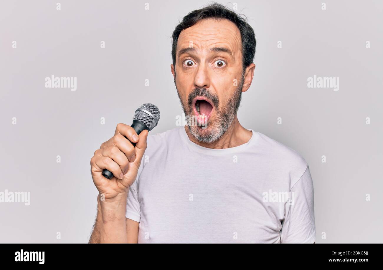 Middle age handsome singer man singing using microphone over isolated ...