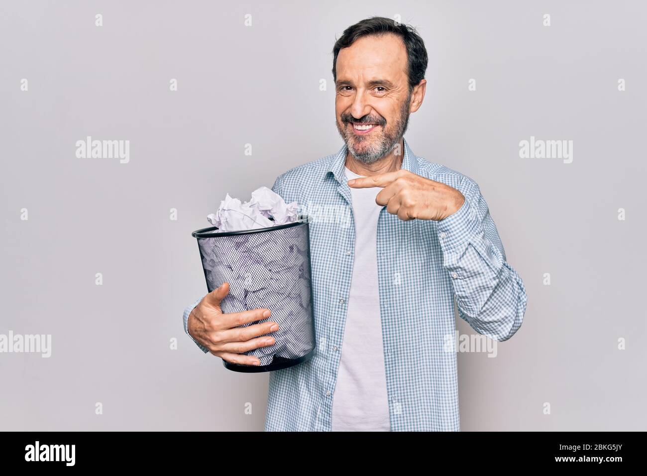 Middle age handsome man holding full paper bin of crumpled papers over ...