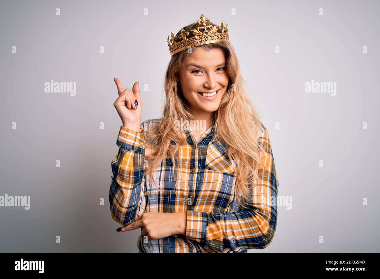 Young beautiful blonde woman wearing golden crown of queen over ...