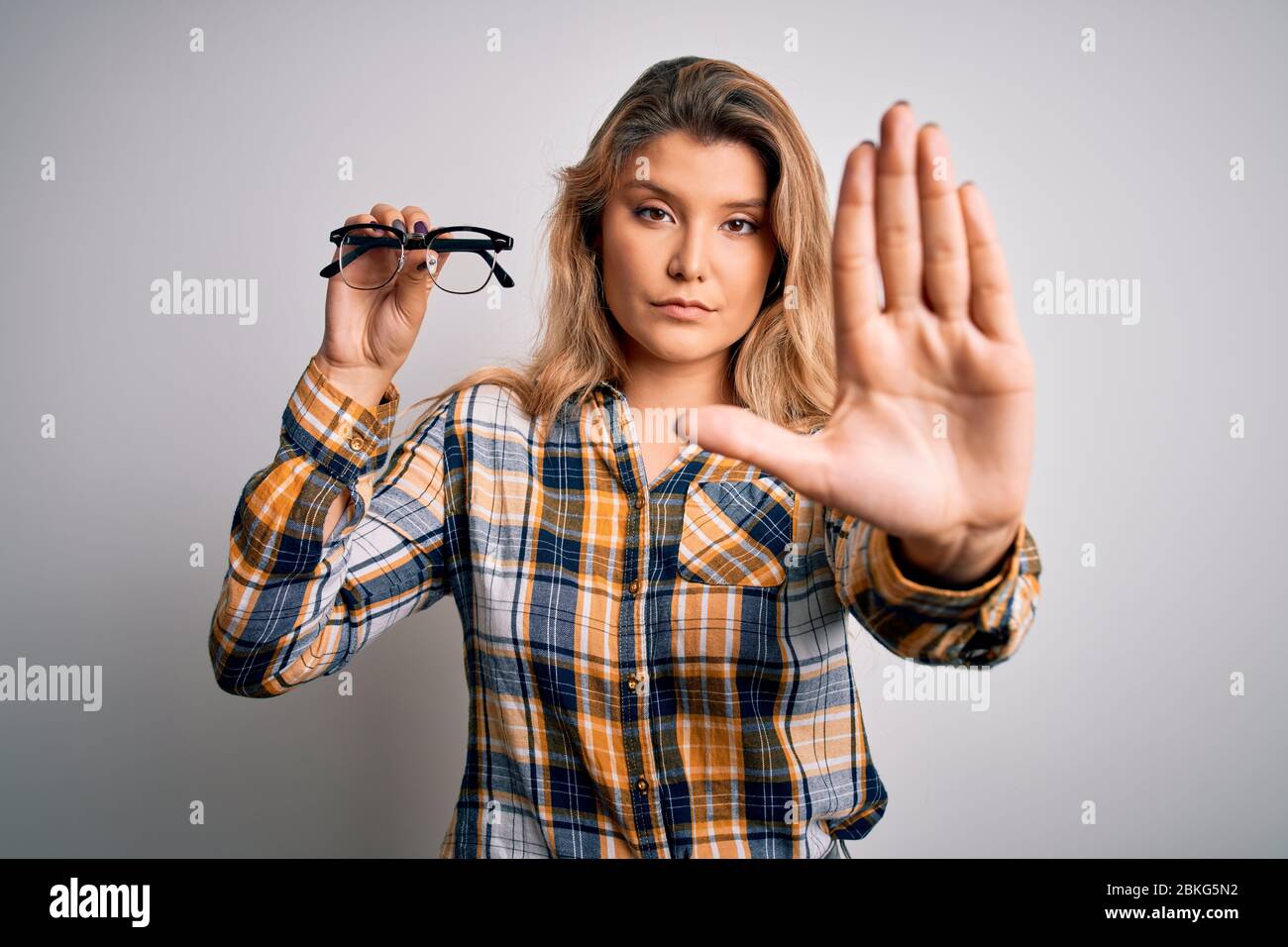 Young beautiful blonde optical woman holding vision glasses over ...