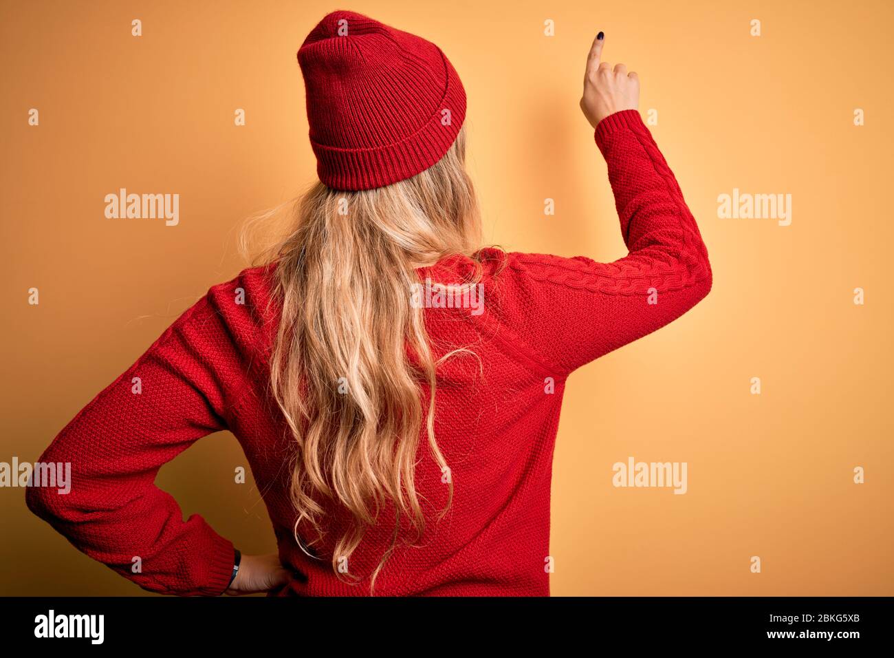 Young beautiful blonde woman wearing casual sweater and wool cap over ...