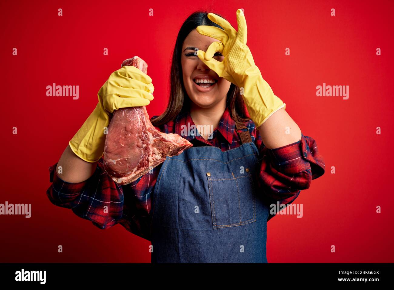 Young butcher woman holding fresh raw beef meat stake over red ...