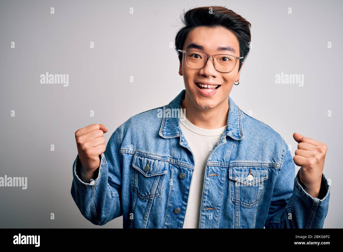 Young handsome chinese man wearing denim jacket and glasses over white ...