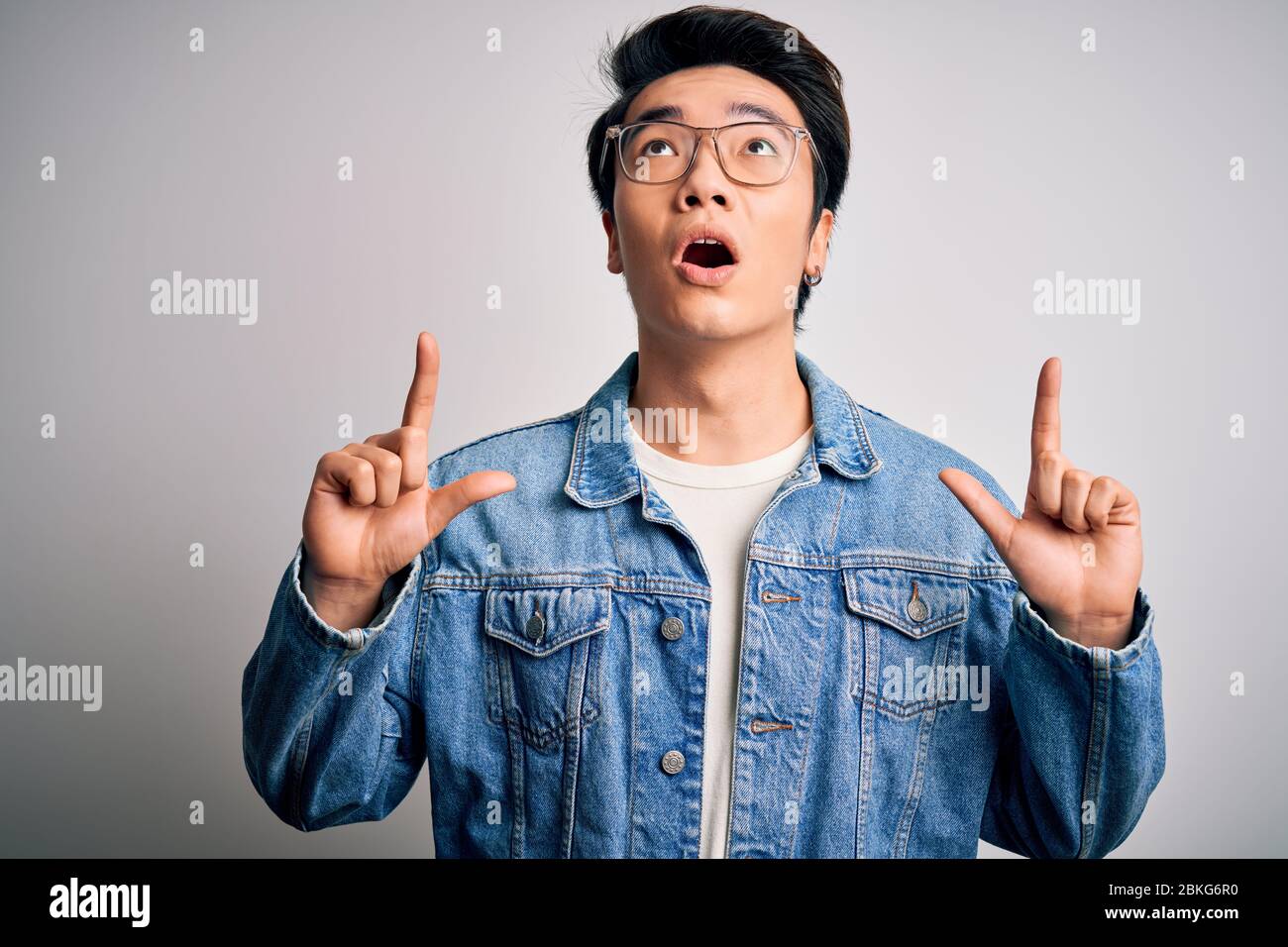 Young handsome chinese man wearing denim jacket and glasses over white ...