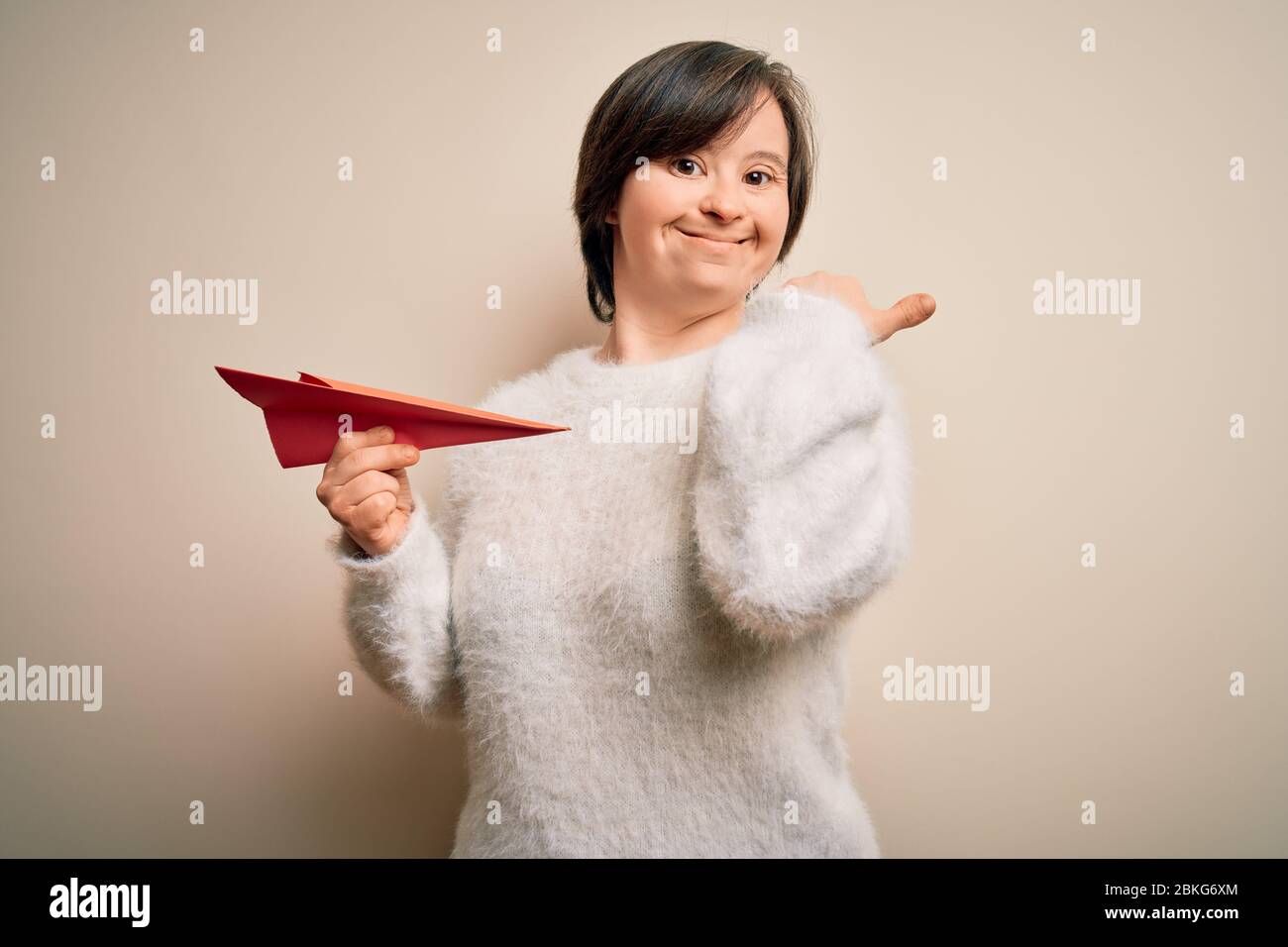 Young down syndrome woman having fun with paper plane as dream of ...