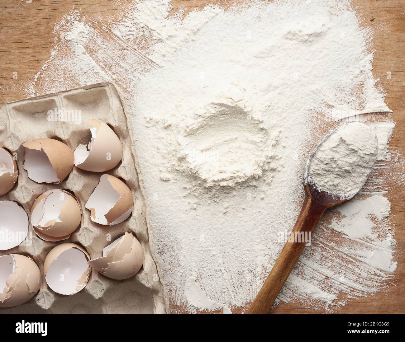 white wheat flour scattered on a brown wooden table, top view, funnel ...
