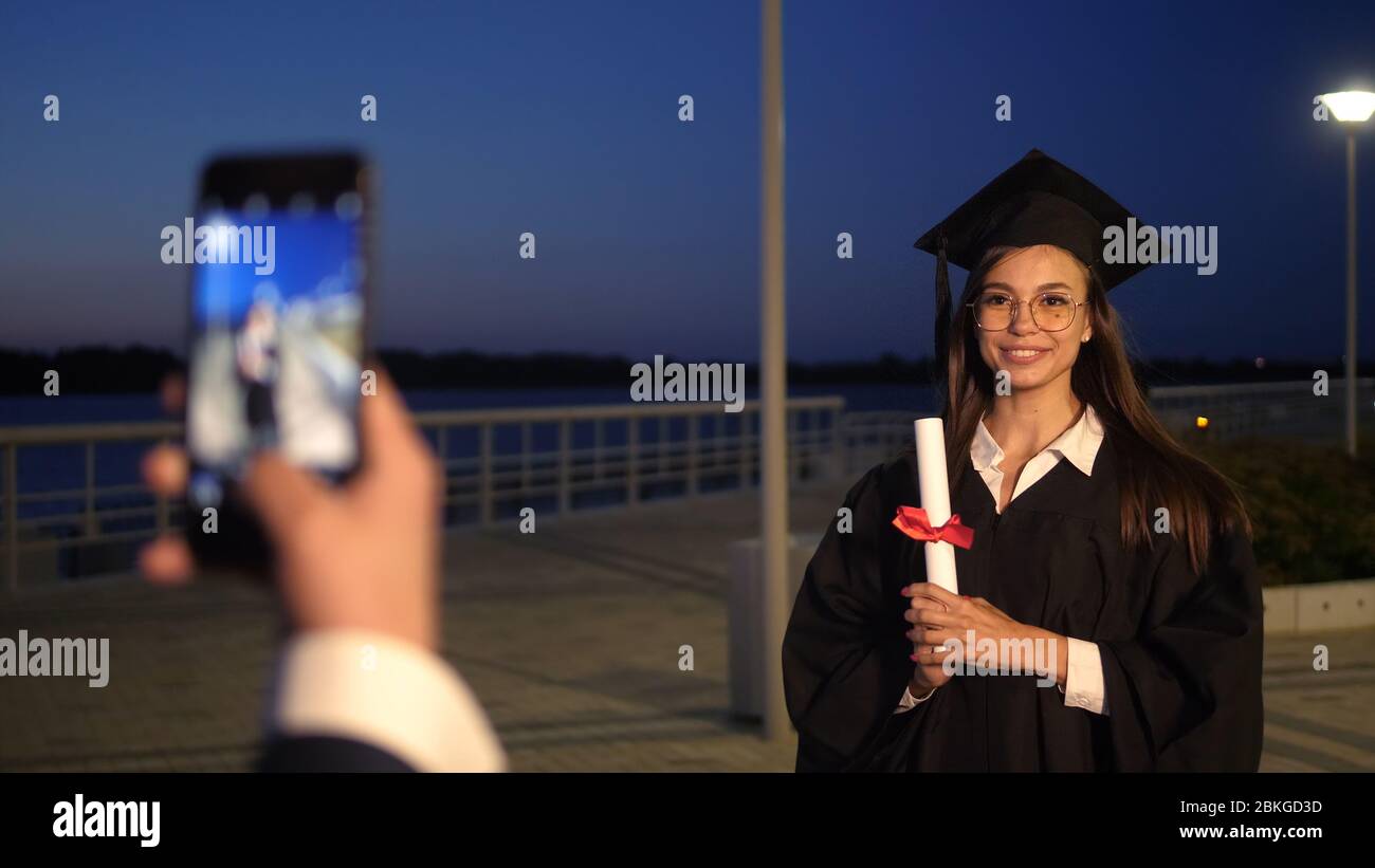 Smiling female graduate student is photographed by her friend Stock ...