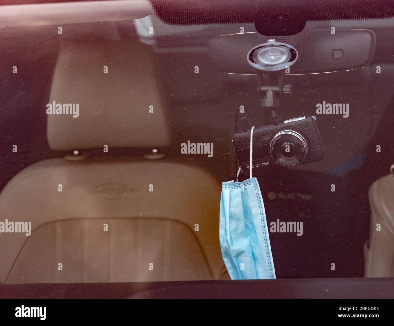 A protective surgical masc hanging from a dashboard camera in a car ...