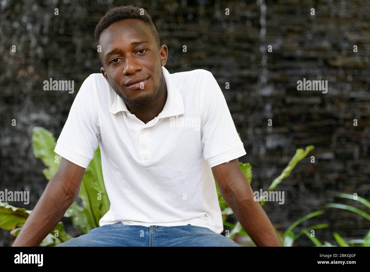 Portrait of young African man sitting in the city outdoors Stock Photo ...