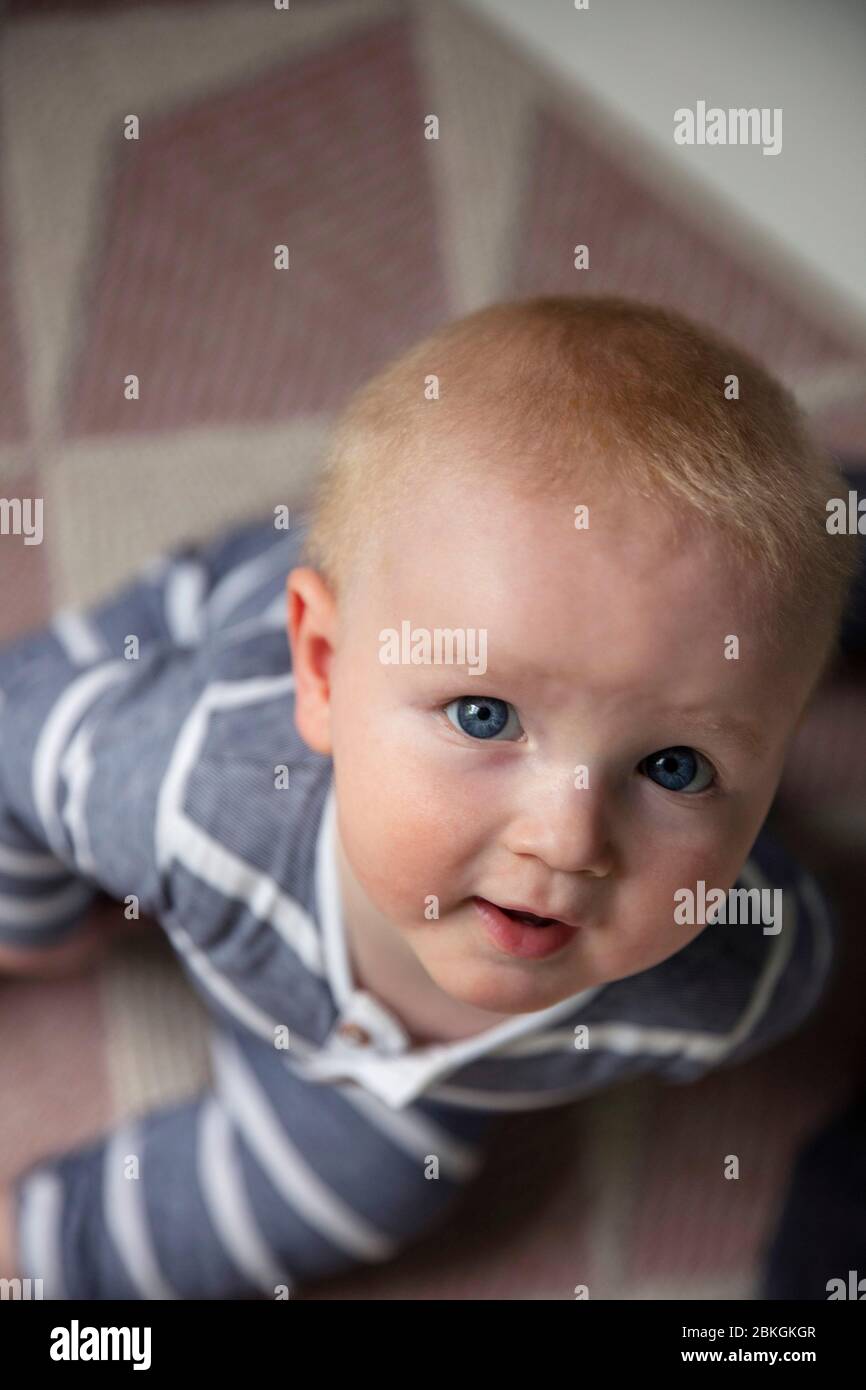 A cute baby boy sat on a nursery floor looking up to the camera Stock ...