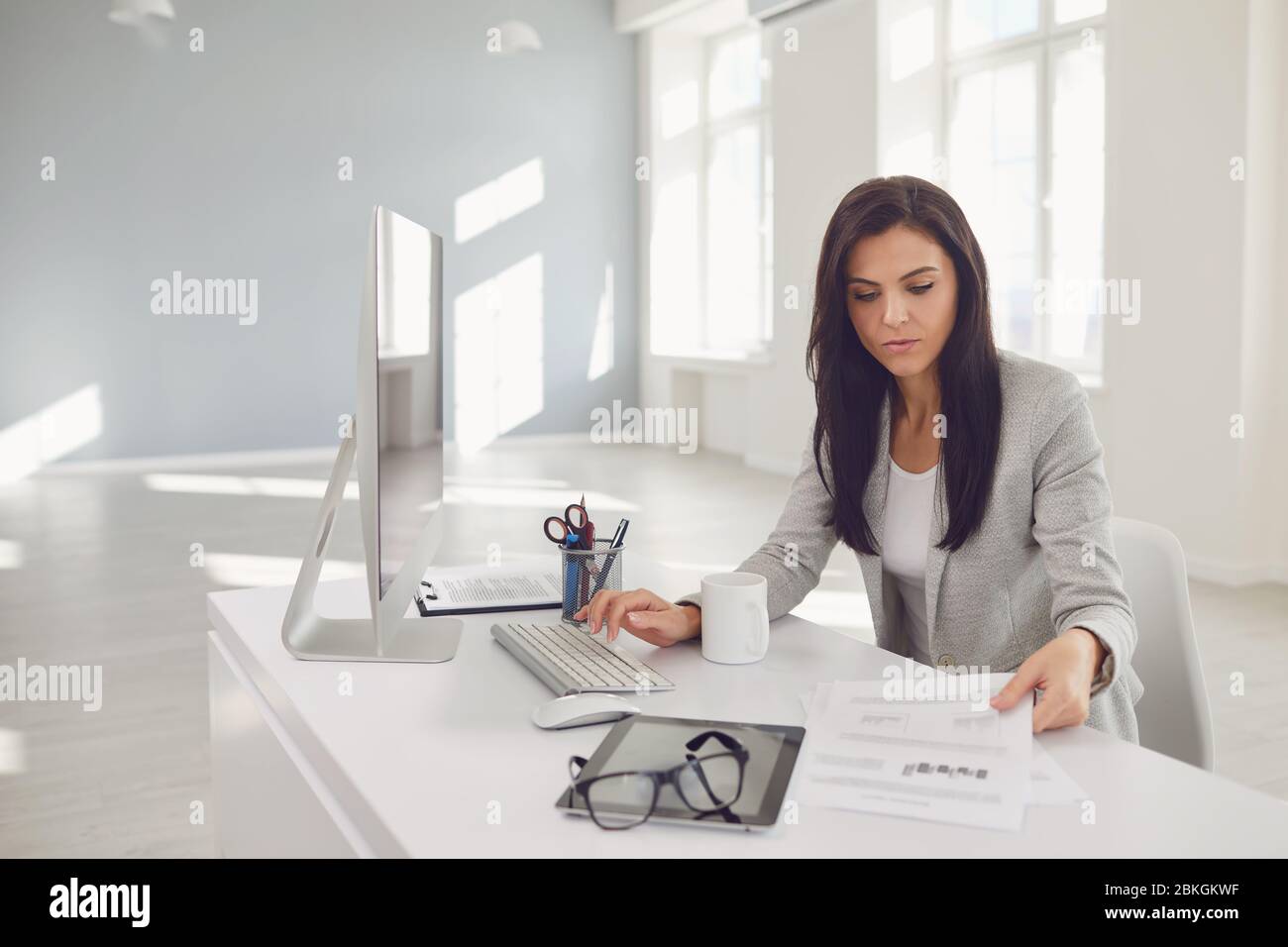 Serious busy businesswoman reads working documents sitting at a table ...