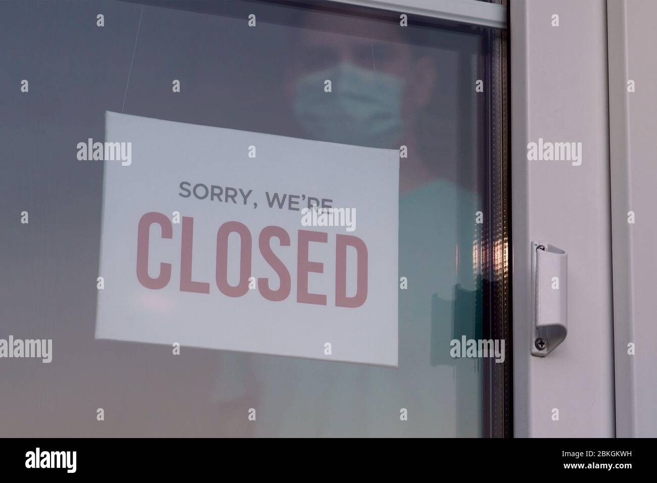 Business owner in medical mask puts a CLOSED sign Stock Photo - Alamy