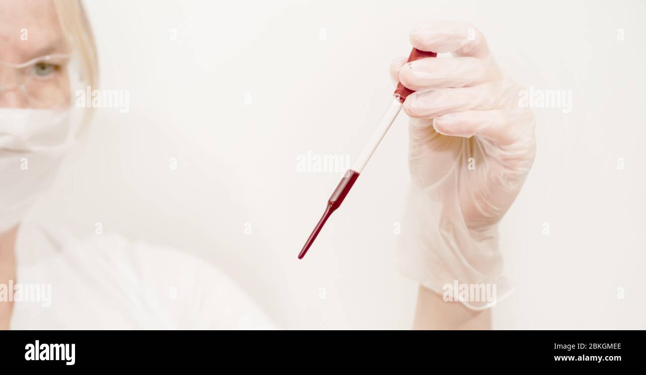 blurred female scientist with blood in pipette on white background ...