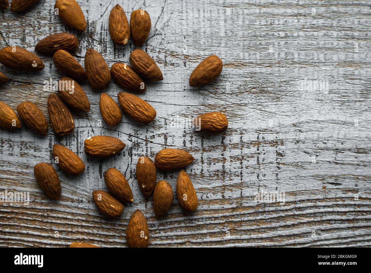 Almonds scattered on the wooden vintage table. Almond is a healthy ...