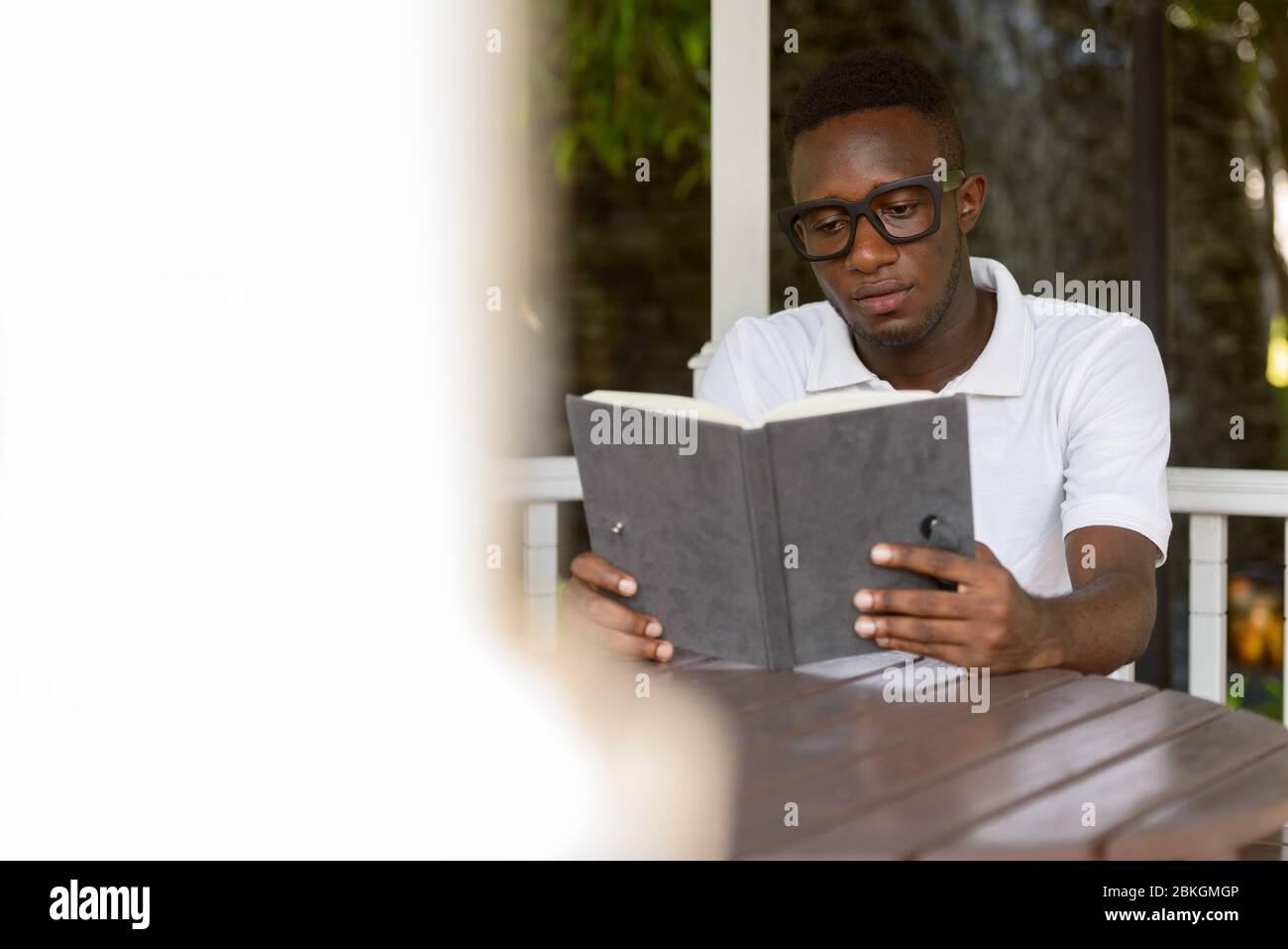 Young African man as student reading book at the park Stock Photo - Alamy