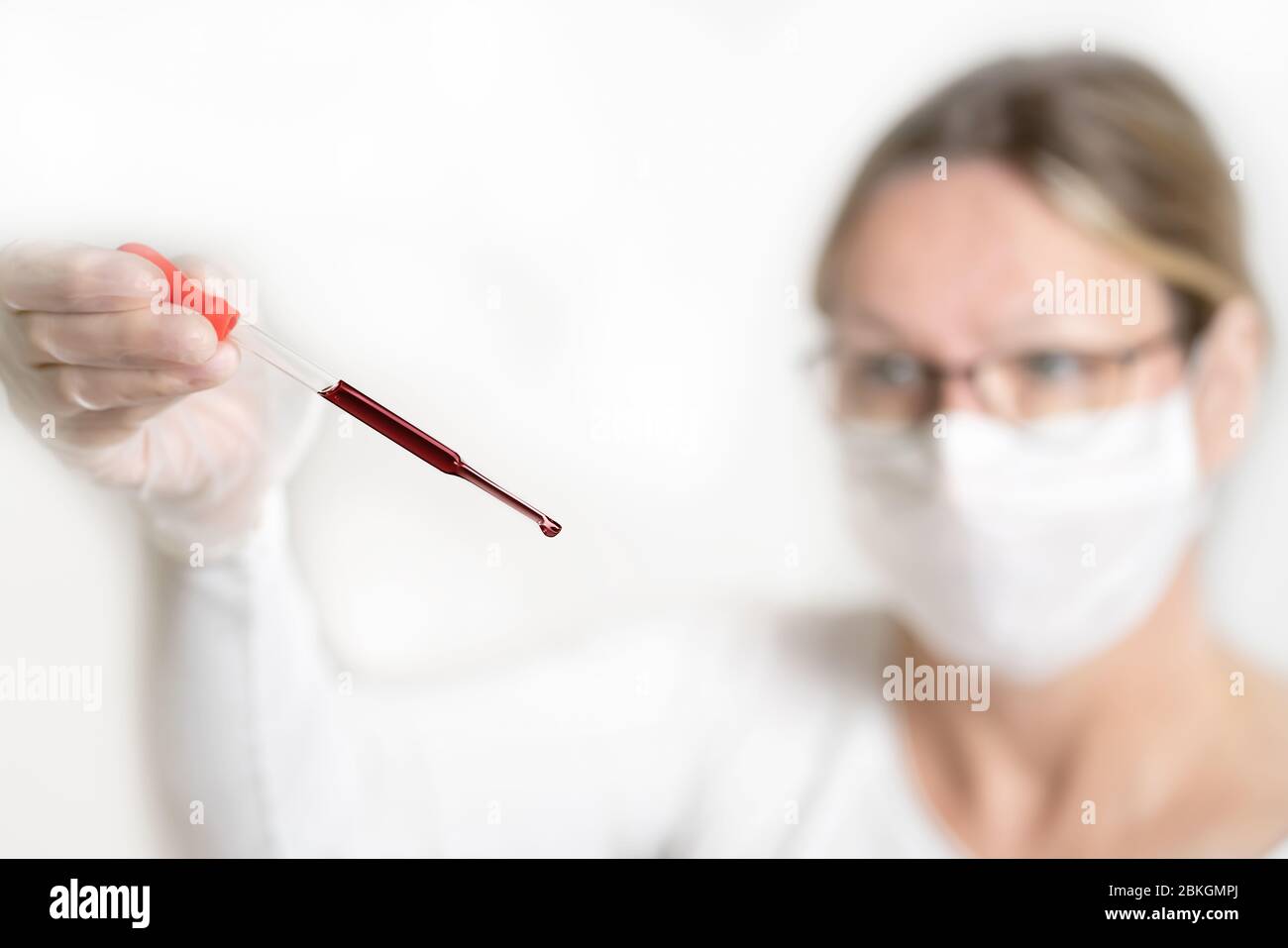 blurred female doctor with blood in pipette isolated on white ...