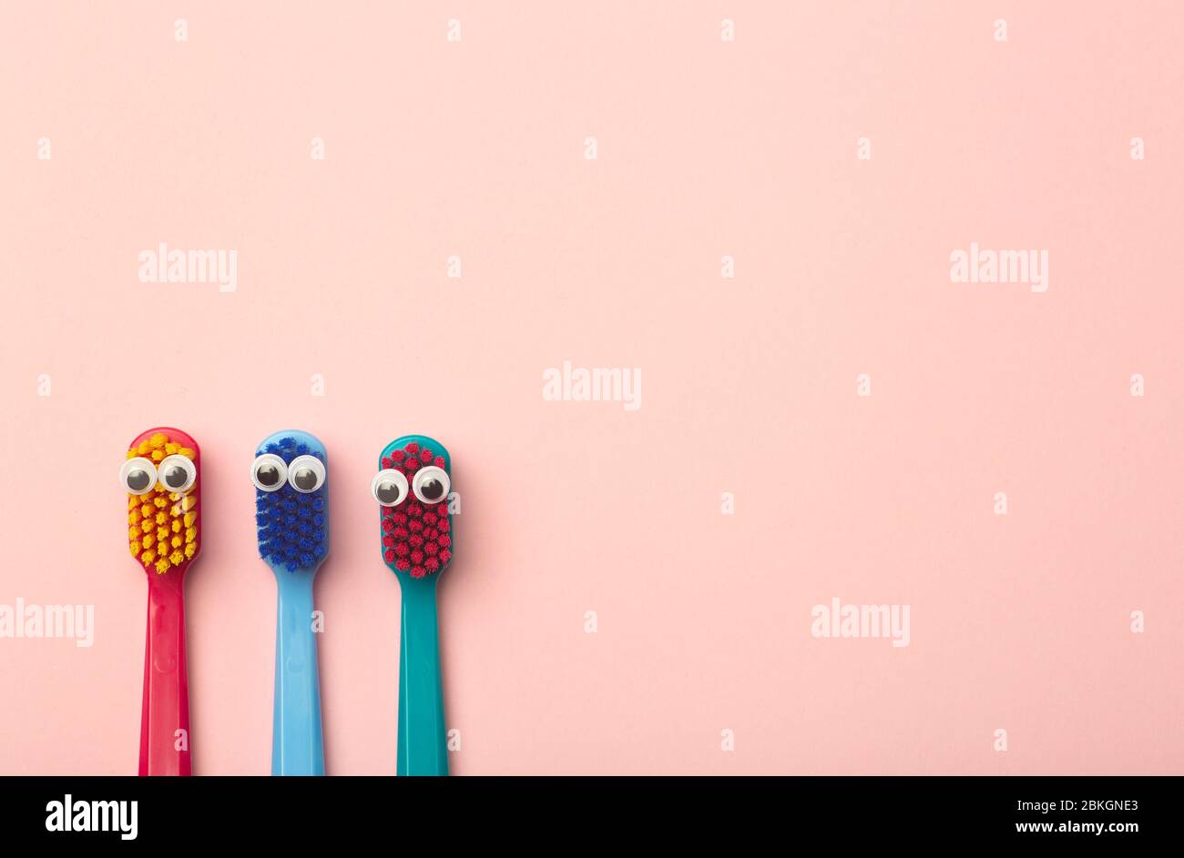 Kids toothbrushes of different colors on a pink background. Teeth and ...