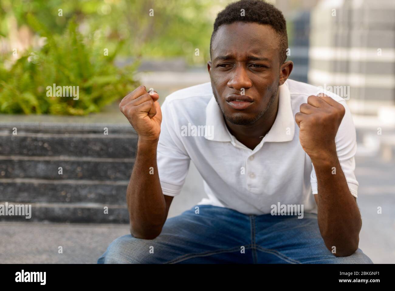 Portrait of stressed young African man looking upset while sitting ...