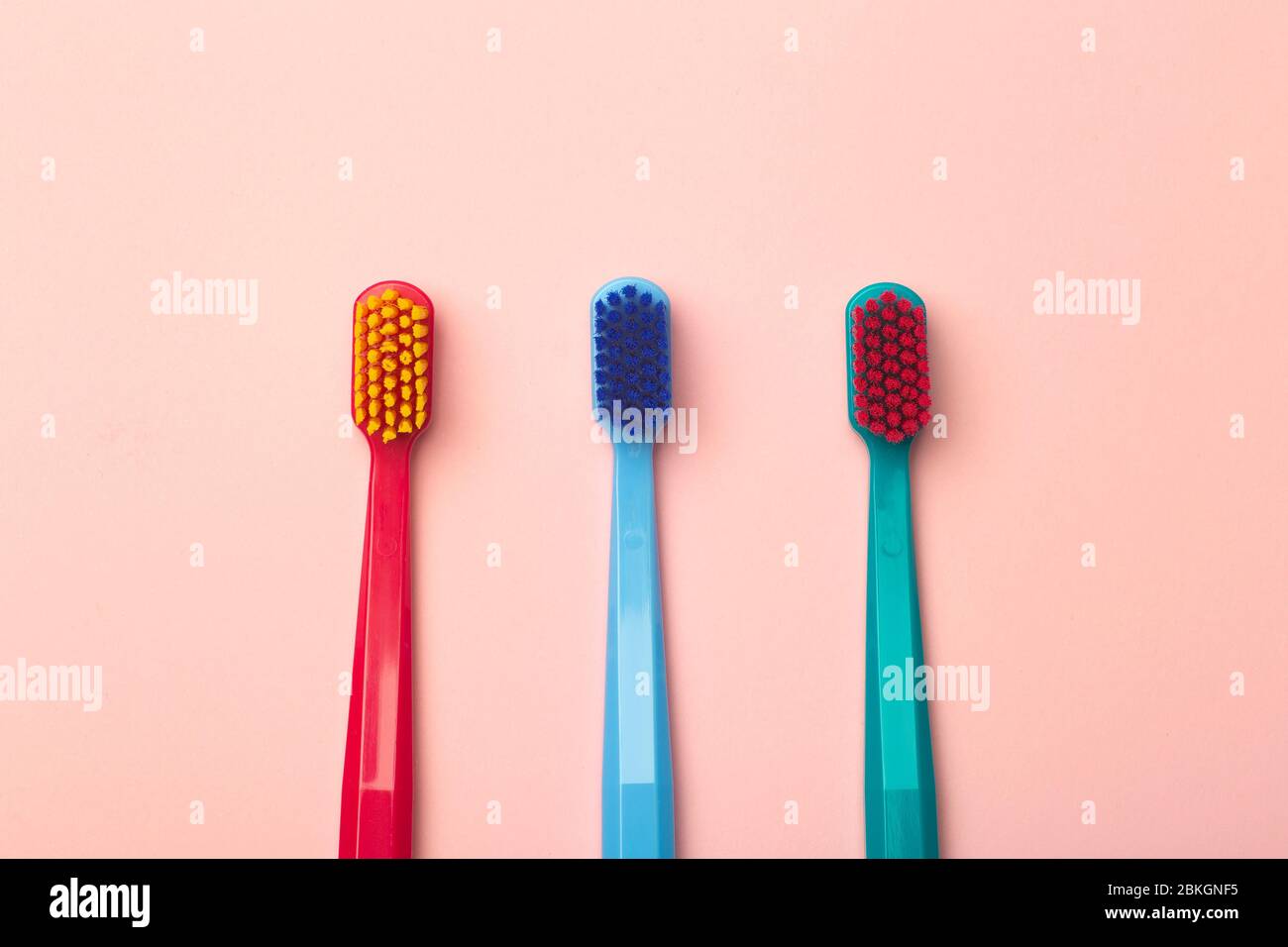 Toothbrushes of different colors on a pink background. Brushing teeth ...