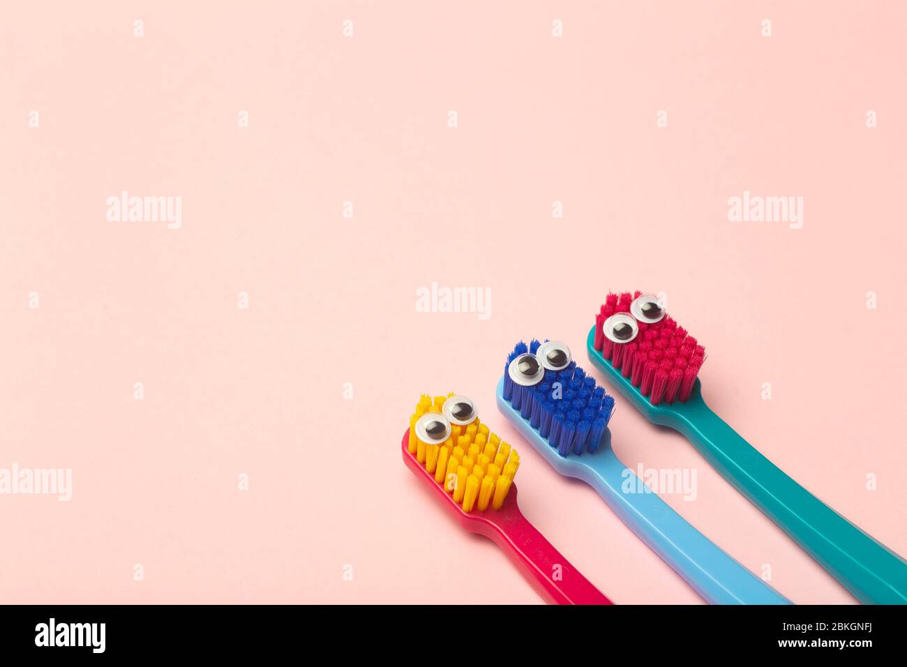 Kids toothbrushes of different colors on a pink background. Teeth and ...