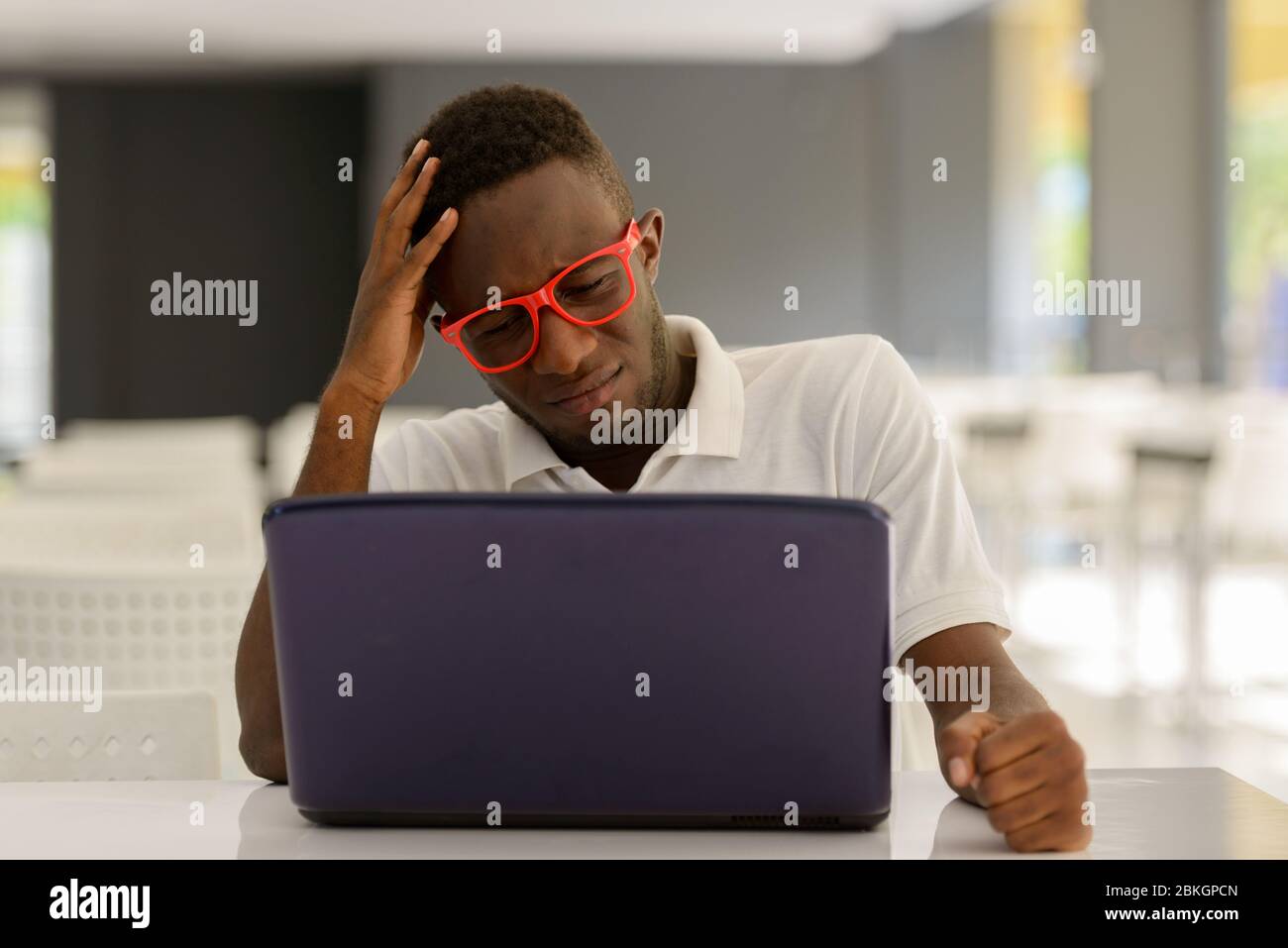 Stressed young African man as student using laptop and getting bad news ...