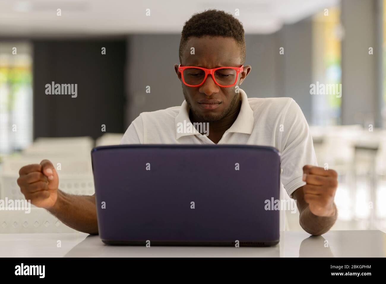 Stressed young African man as student using laptop and getting bad news ...