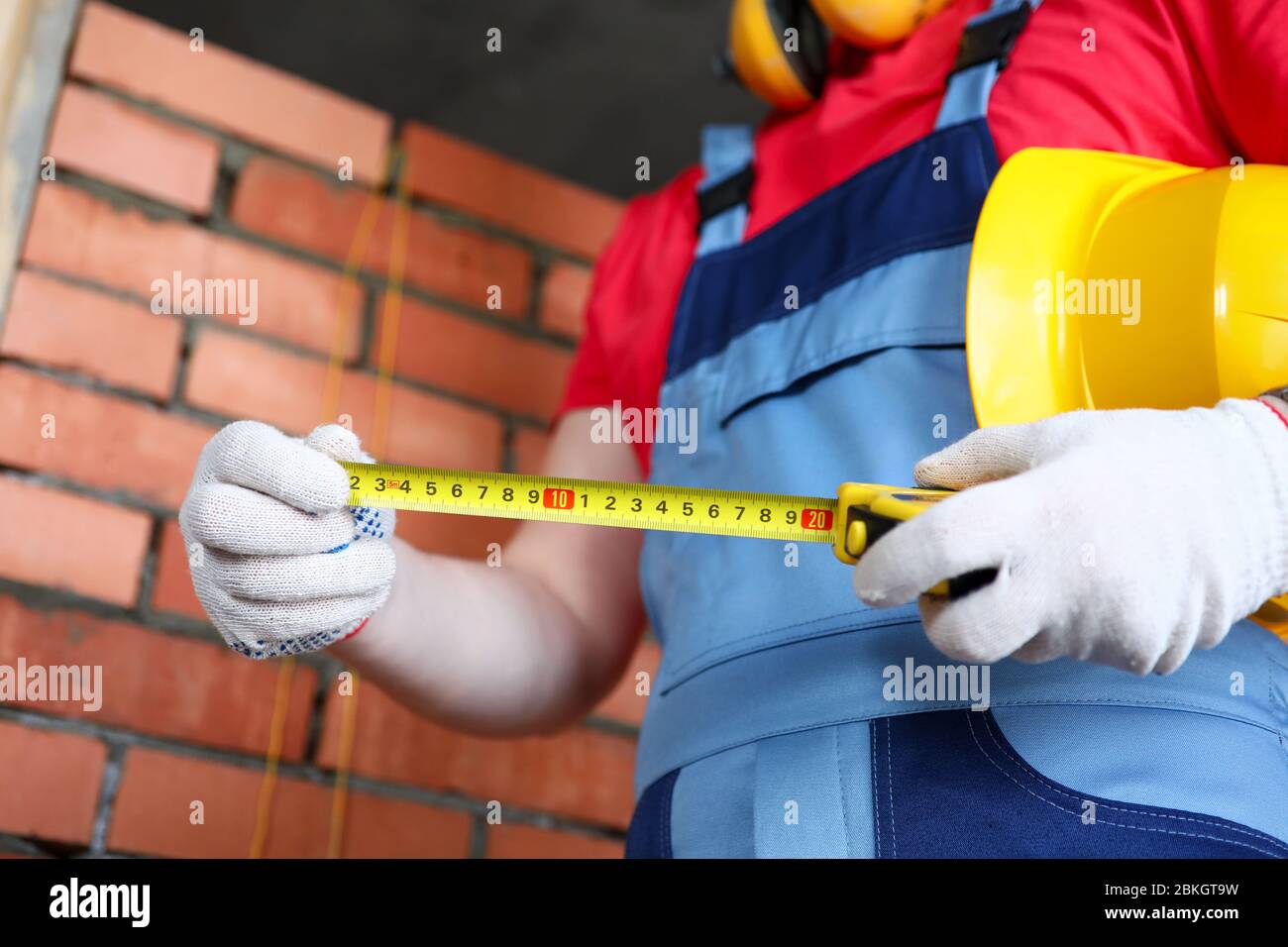 Builder measures dimensions brickwork with tape Stock Photo - Alamy