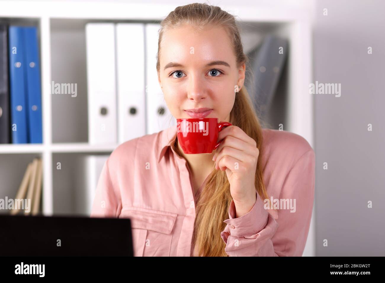 Girl sits office front computer and drinks coffee Stock Photo - Alamy