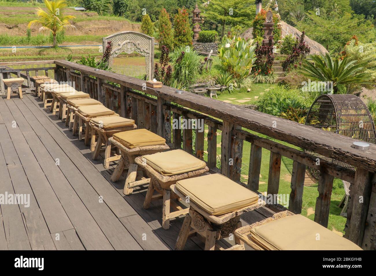 Row of wooden stools with cushions on terrace with floor made of planed ...