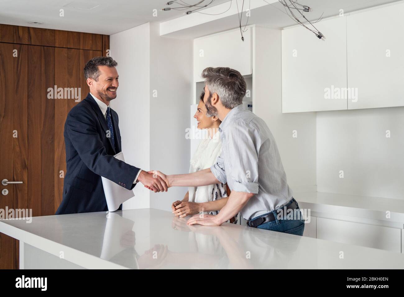 Real estate agent greeting couple Stock Photo - Alamy