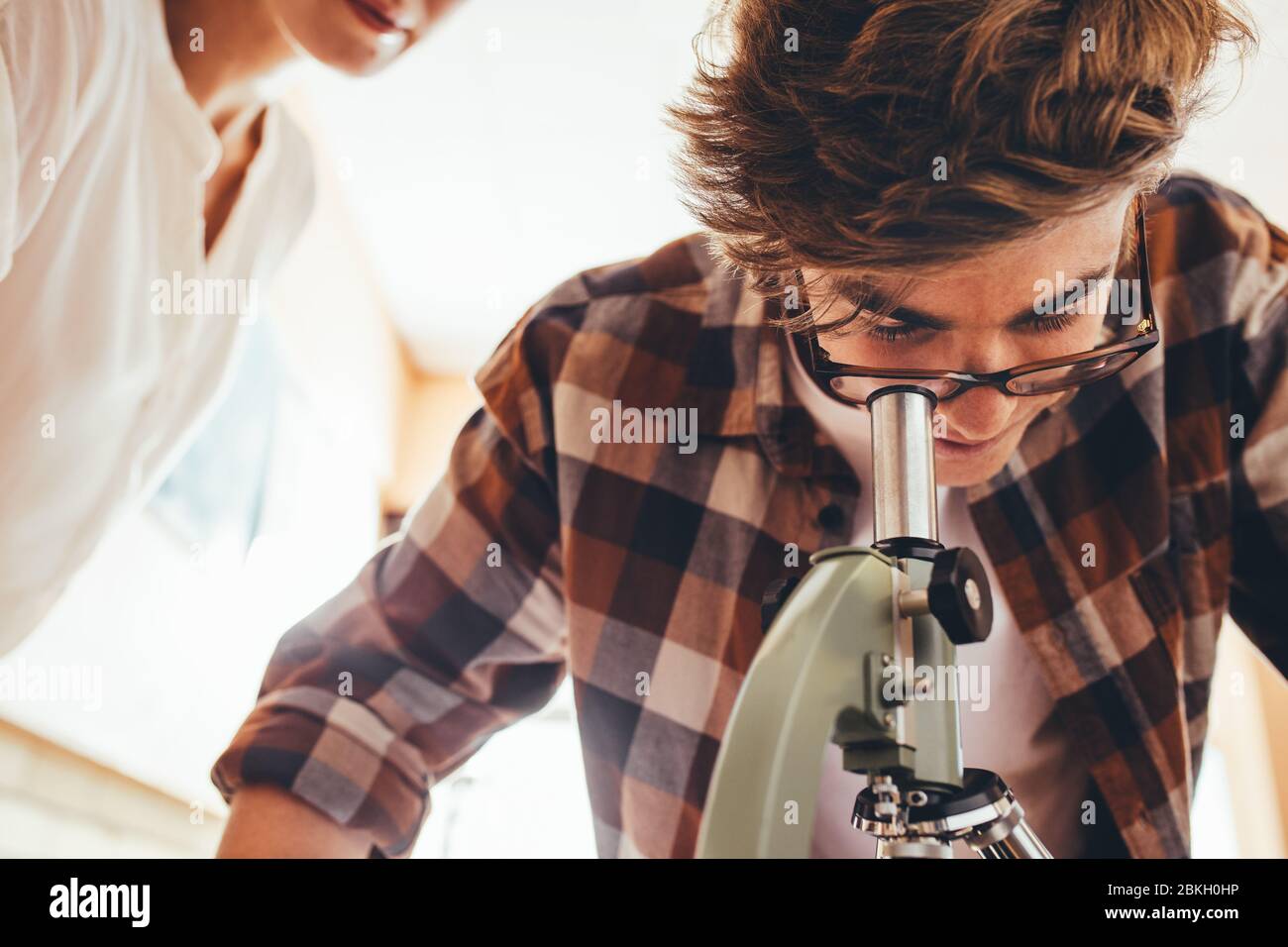 Boy with female teacher in school laboratory looking in a microscope ...