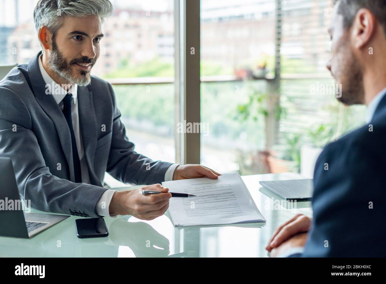 Businessmen discussing document in office Stock Photo - Alamy