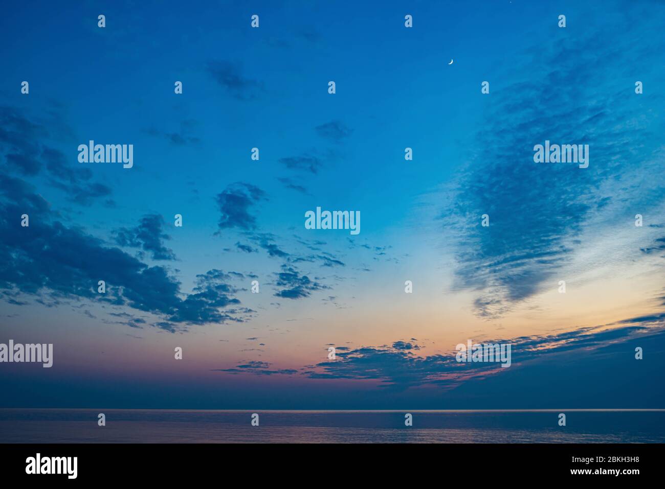 Sunset over Baltic sea. Moon on the cloudy blue sky. Horizon line Stock ...