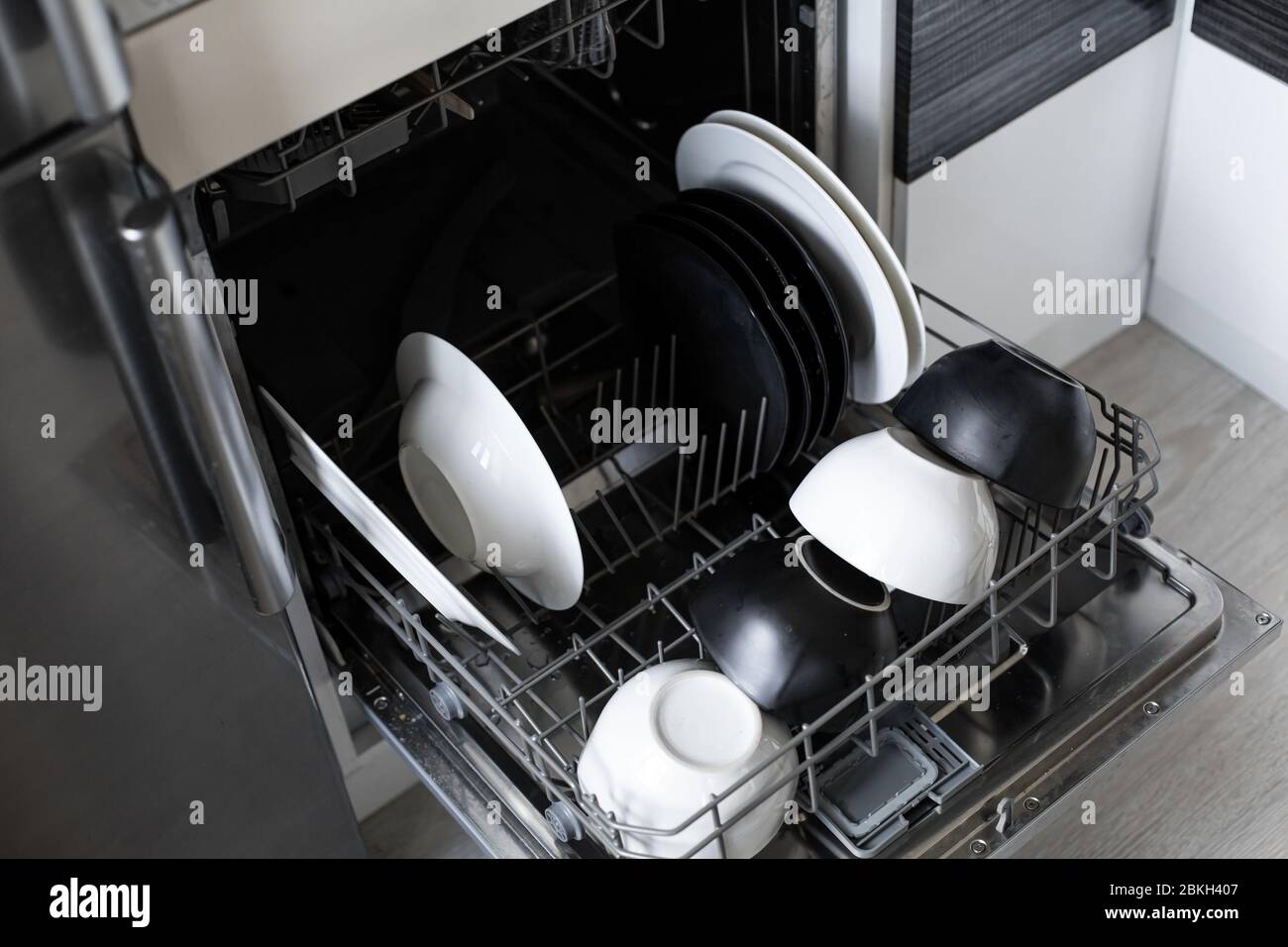 Loading dirty dishes in the dishwasher close up Stock Photo - Alamy