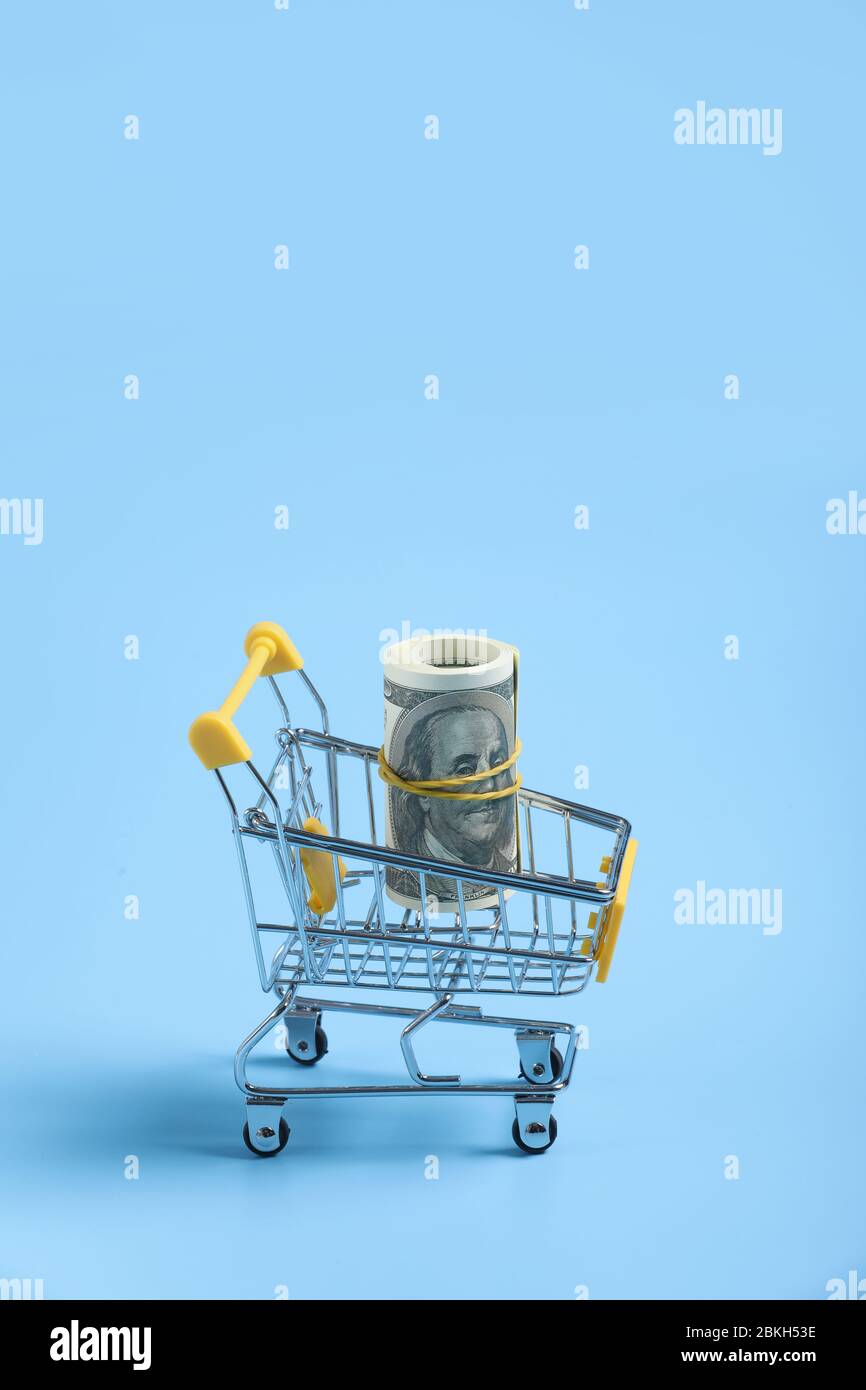 Small shopping trolley, cart with dollars banknotes roll inside ...