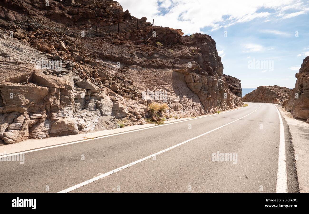 Rocky Road. An empty road curving into the rocky desert hillside in a ...