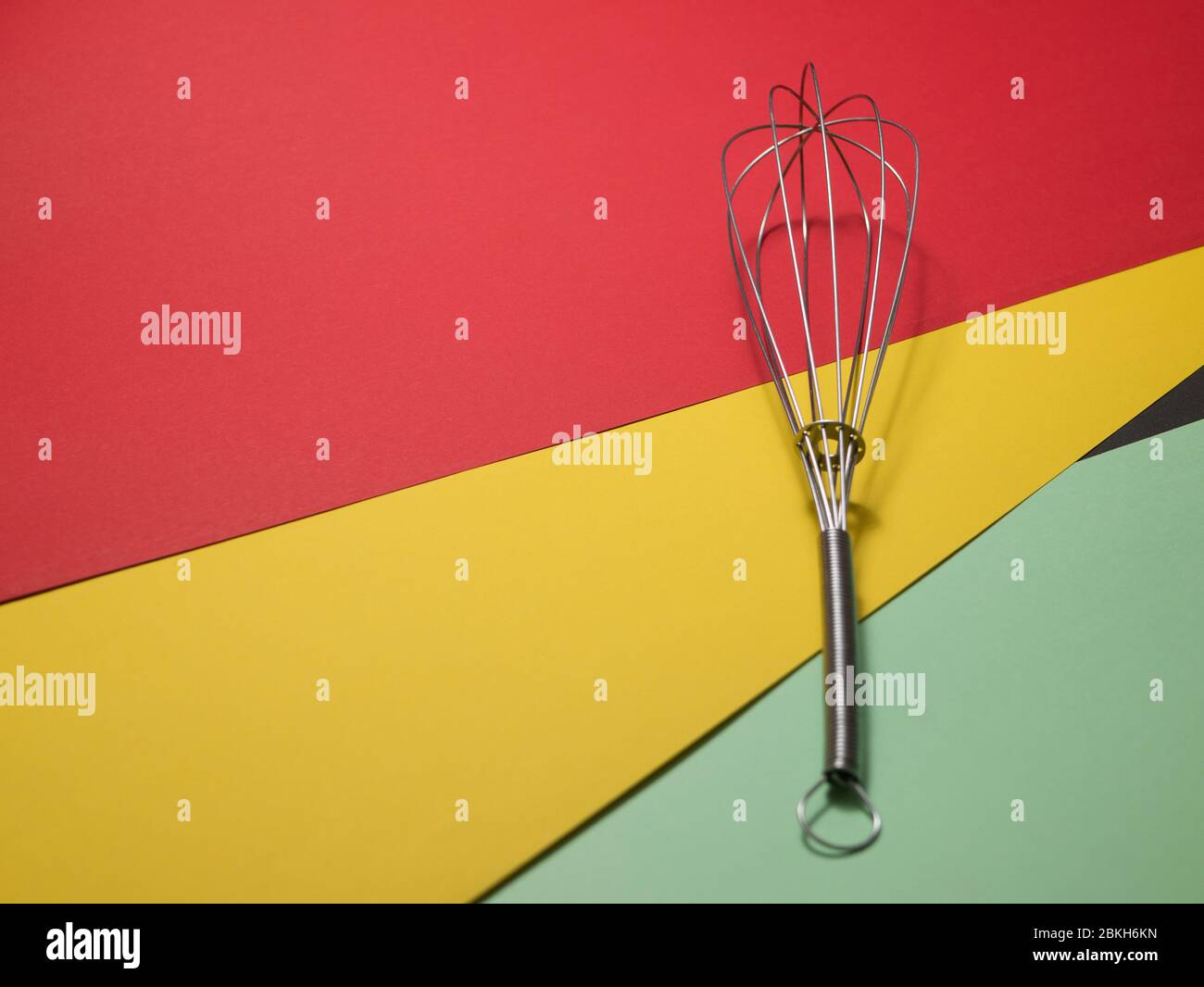 Stainless steel whisk isolated on colored background Stock Photo - Alamy