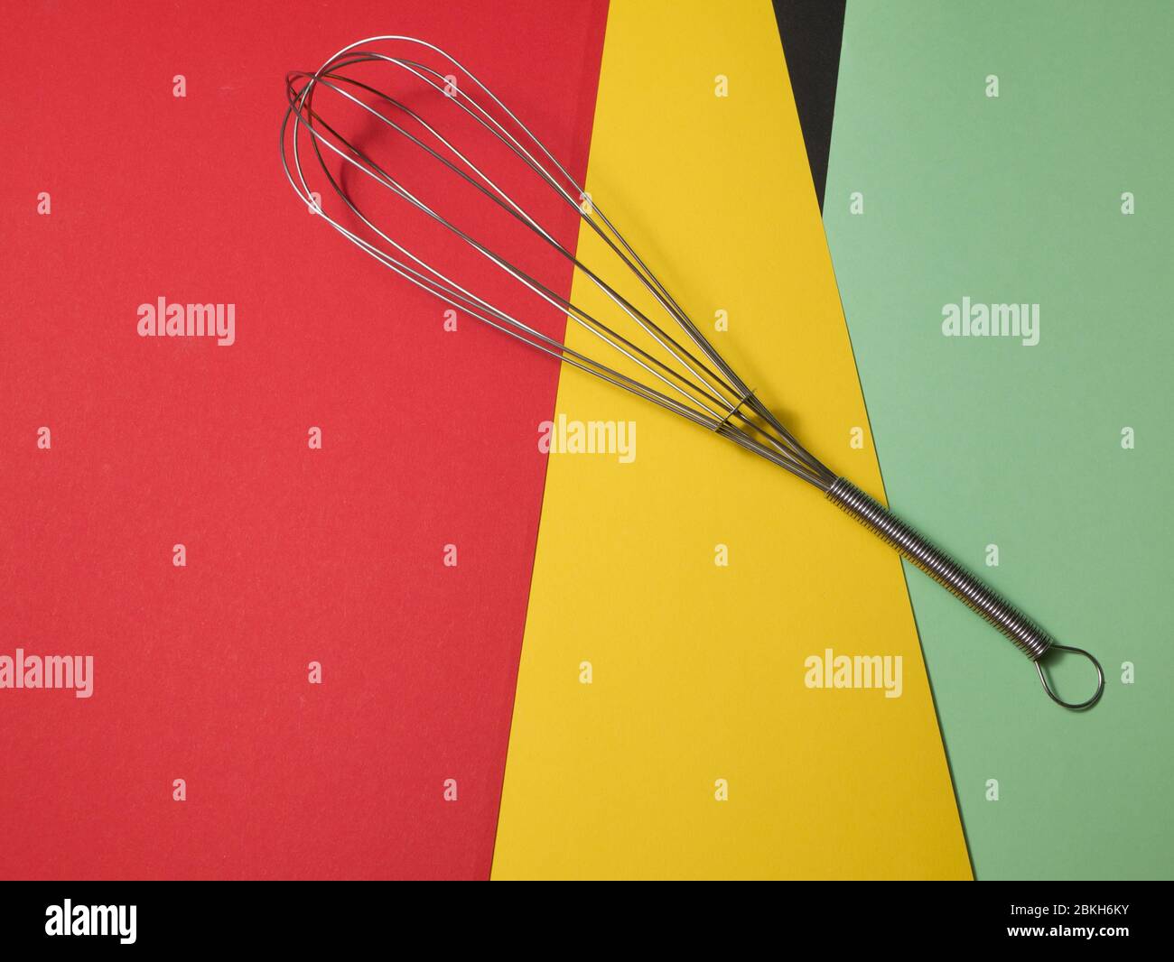 Stainless steel whisk isolated on colored background Stock Photo - Alamy