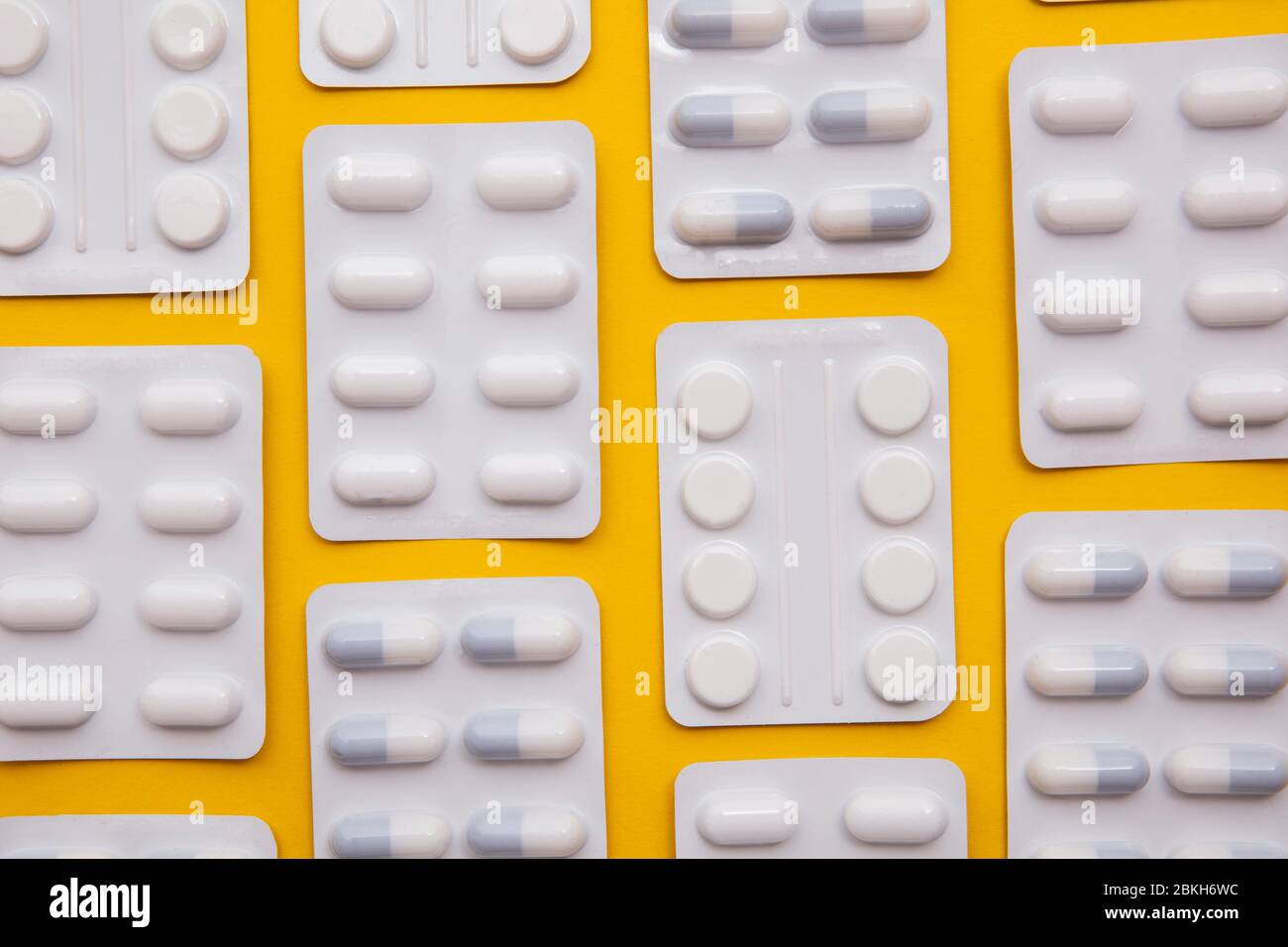 packets of medical drug pills and tablets on a bright yellow background ...