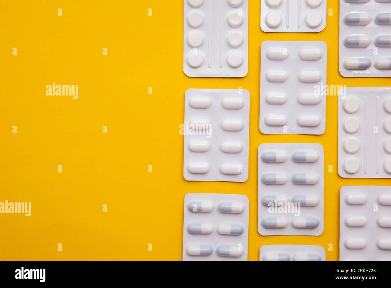 packets of medical drug pills and tablets on a bright yellow background ...