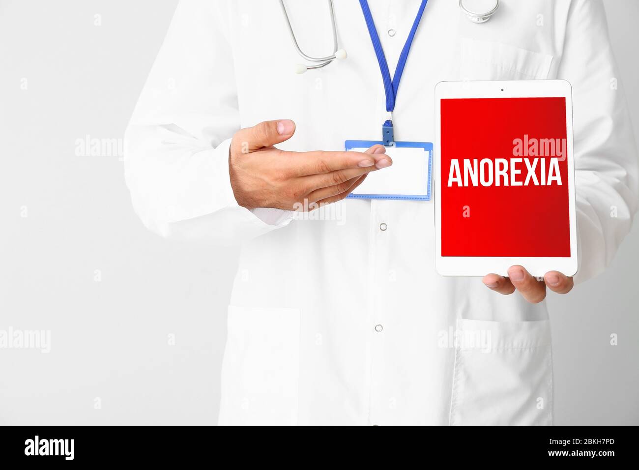 Male doctor holding tablet computer with word ANOREXIA on screen ...