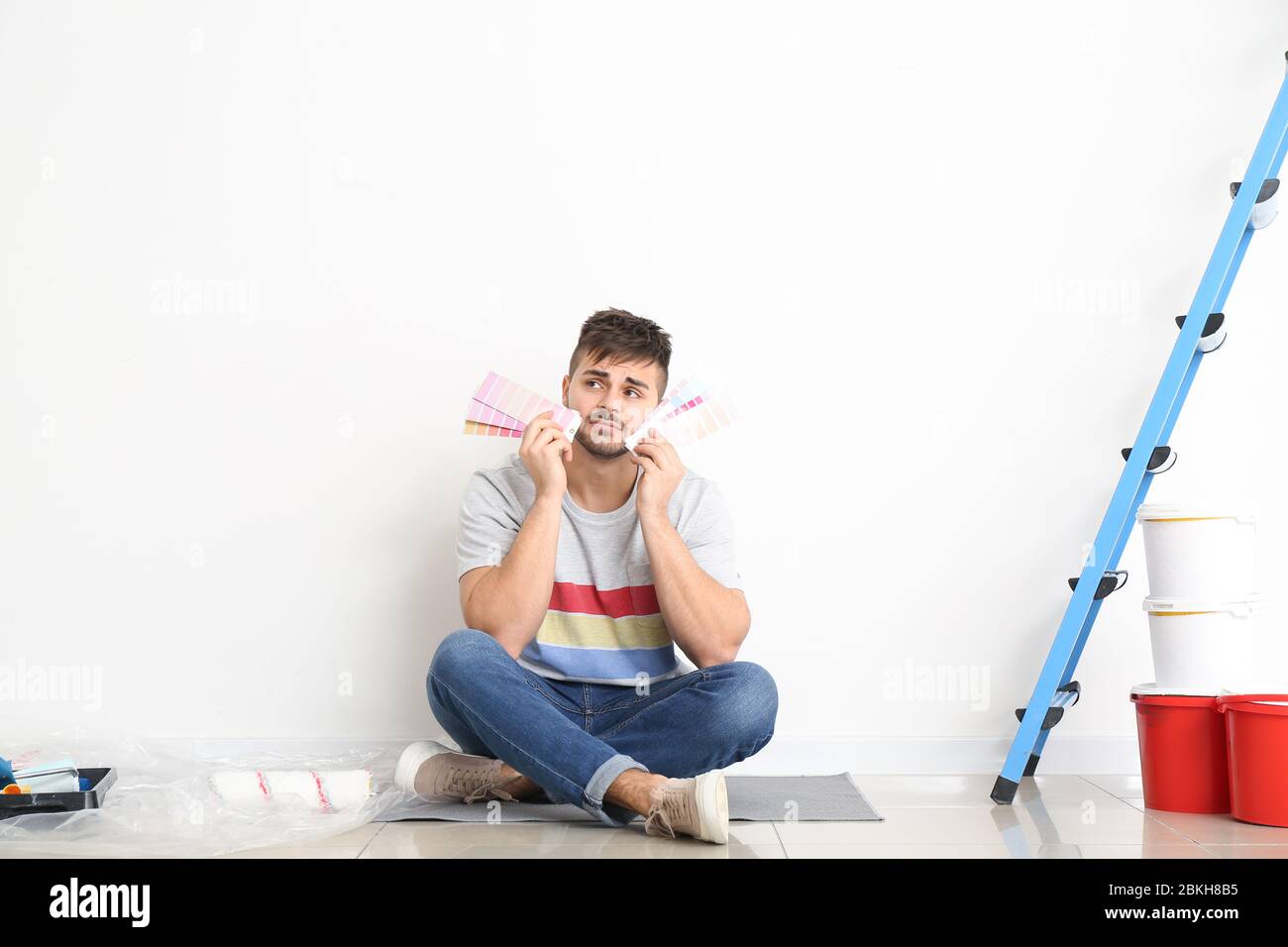 Sad man choosing color of wall indoors Stock Photo - Alamy