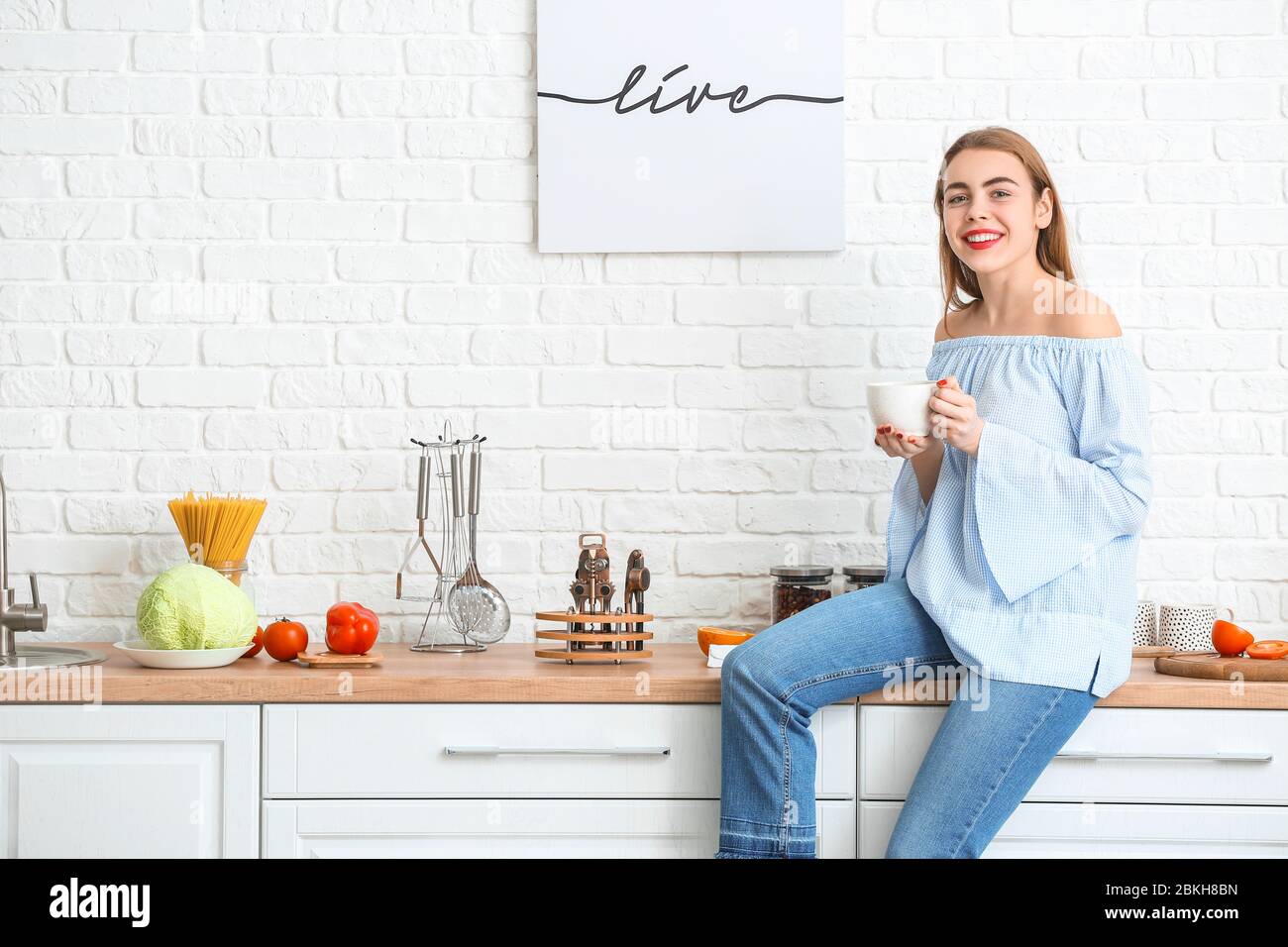 Beautiful young woman drinking tea in kitchen Stock Photo - Alamy
