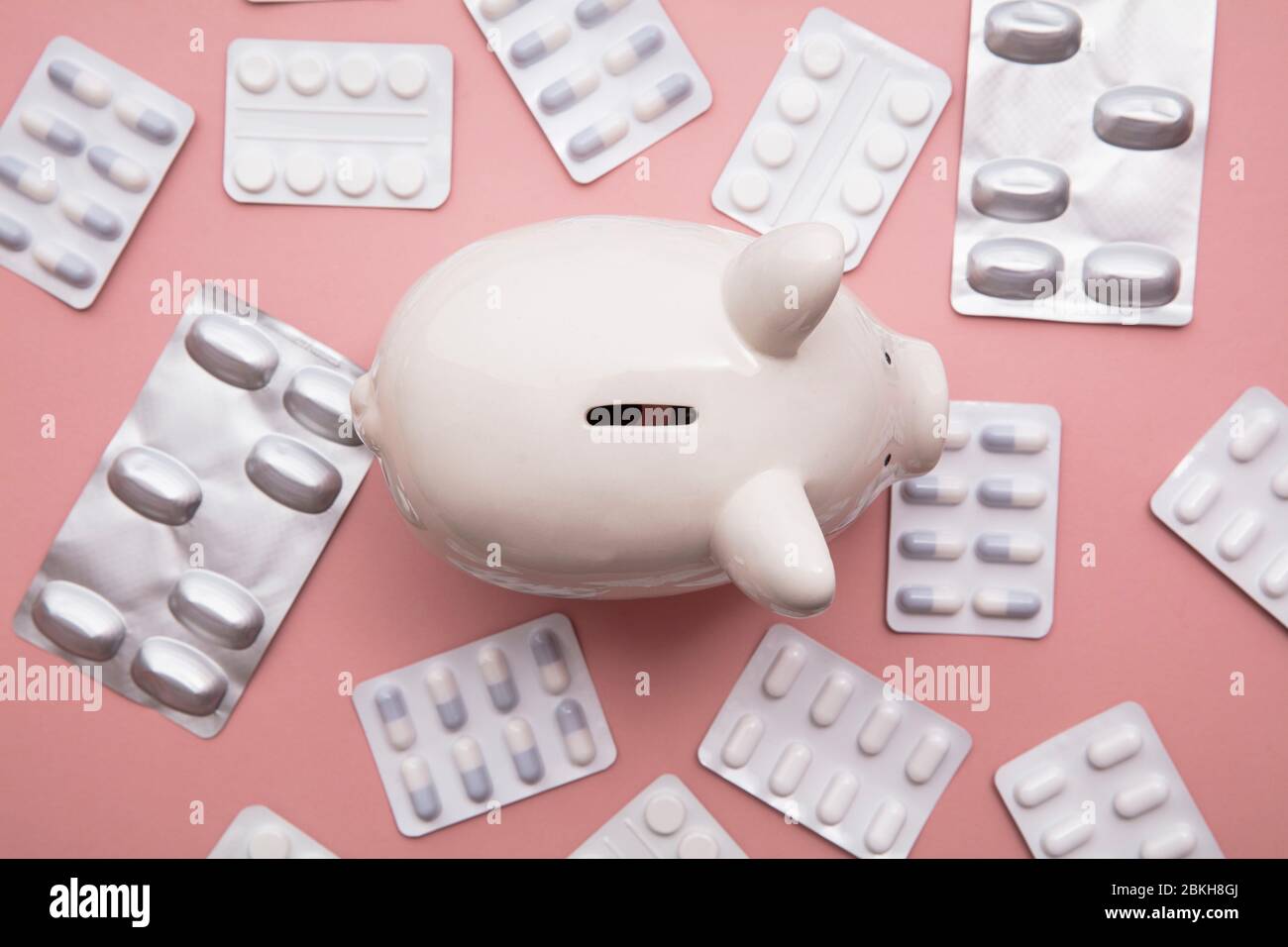 Healthcare cost. Money box piggy bank with packets of pills and tablet ...