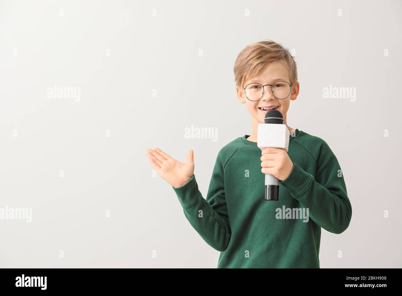 Little journalist with microphone on white background Stock Photo - Alamy