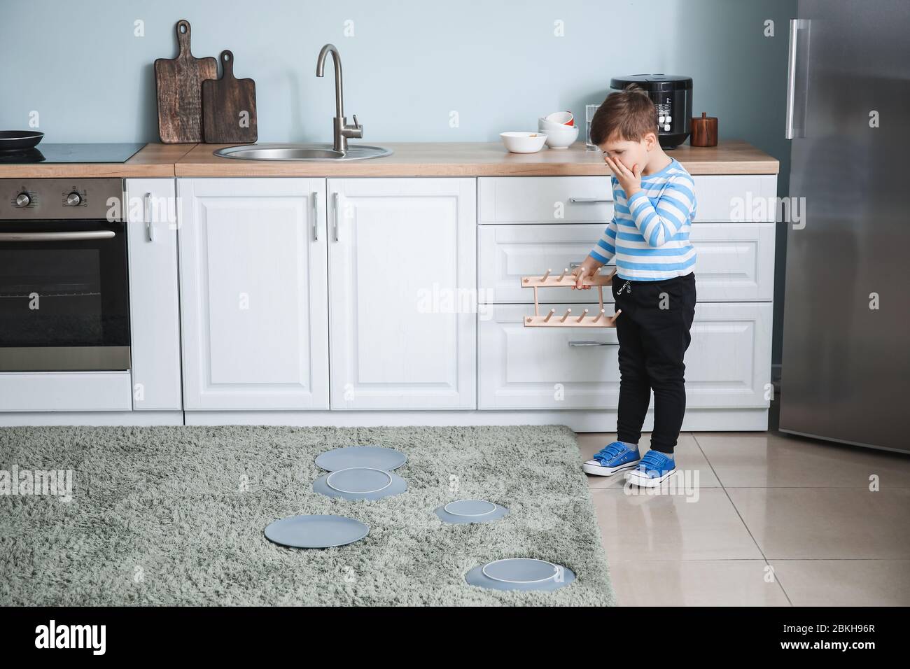 Shocked little boy with fallen plates at home Stock Photo - Alamy