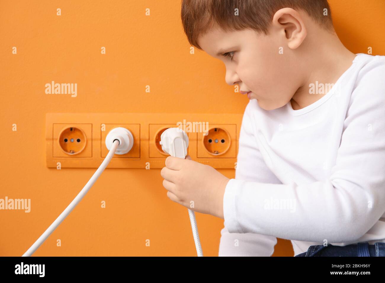 Little boy playing with electric socket at home Stock Photo - Alamy